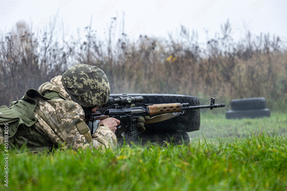Sniper operator in camouflage uniform and body armor shoots from ...