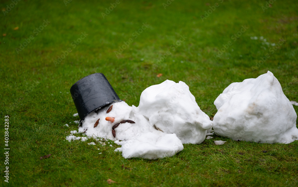 A melted snow man with a sad face as symbol of the end of the winter ...