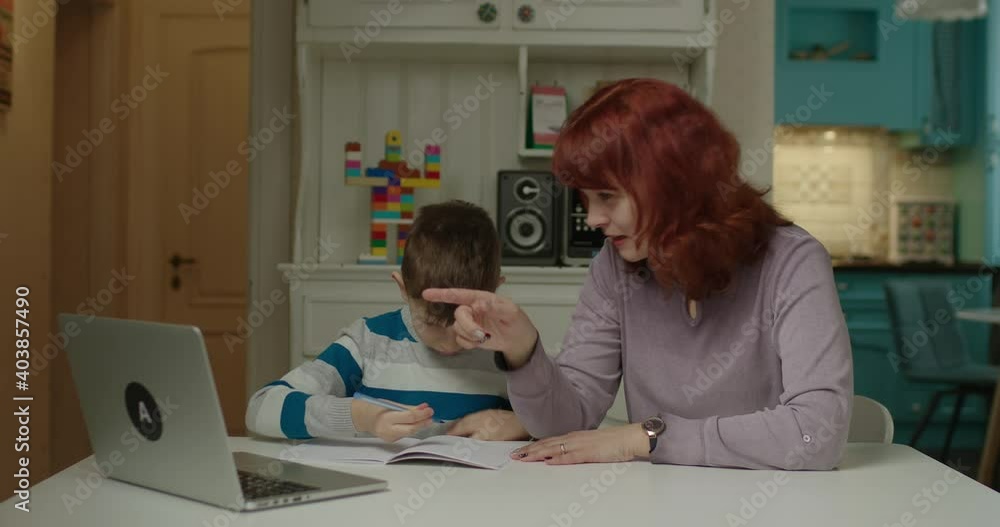 Mother helping son with autism to make homework for online school ...