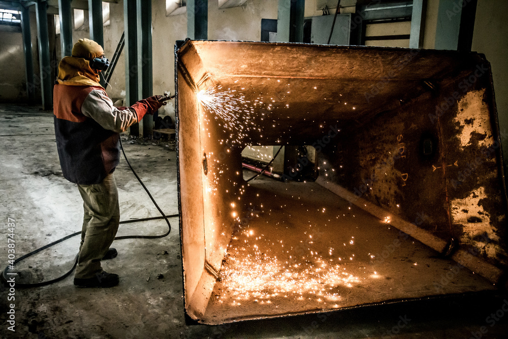 Demolition construction worker using a flame torch to cut up heavy ...