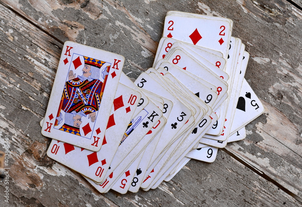 Pile of playing cards at a rustic wooden board. Stock Photo | Adobe Stock