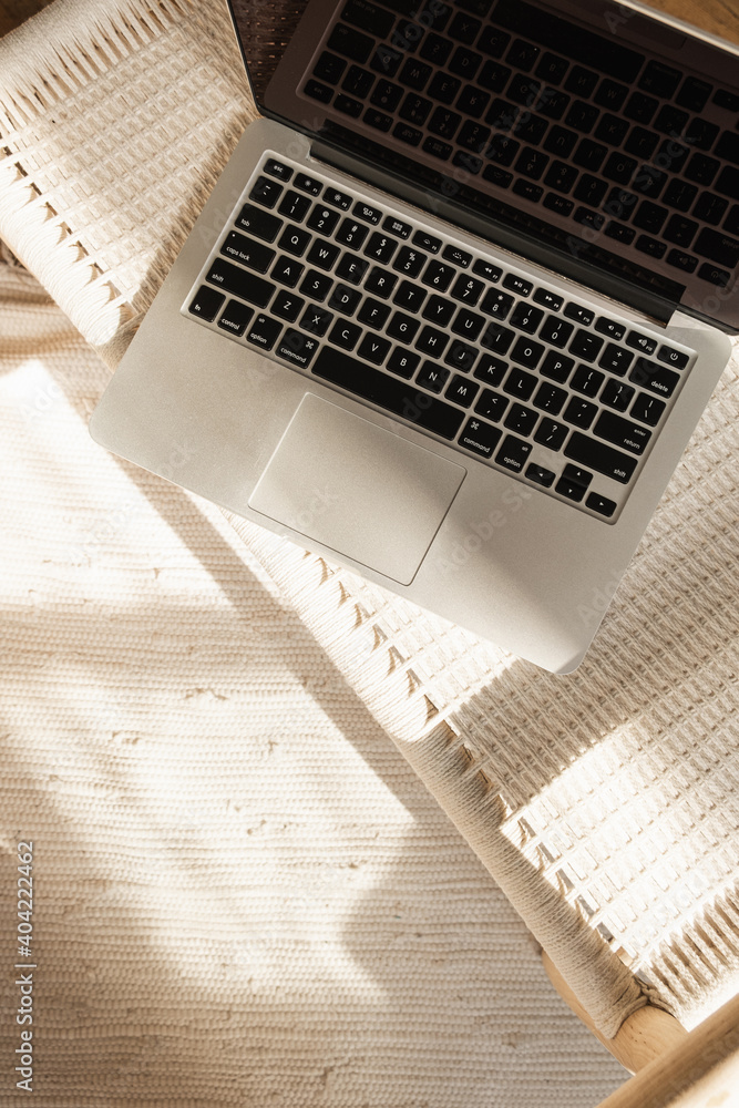 Laptop keyboard and wicker bench on wooden floor. Flat lay, top view ...