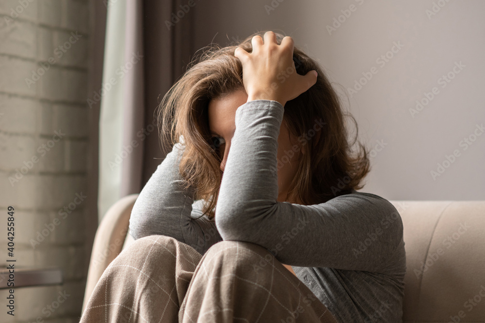 Foto de Sad scared woman in panic attack grabbing her head by hand ...