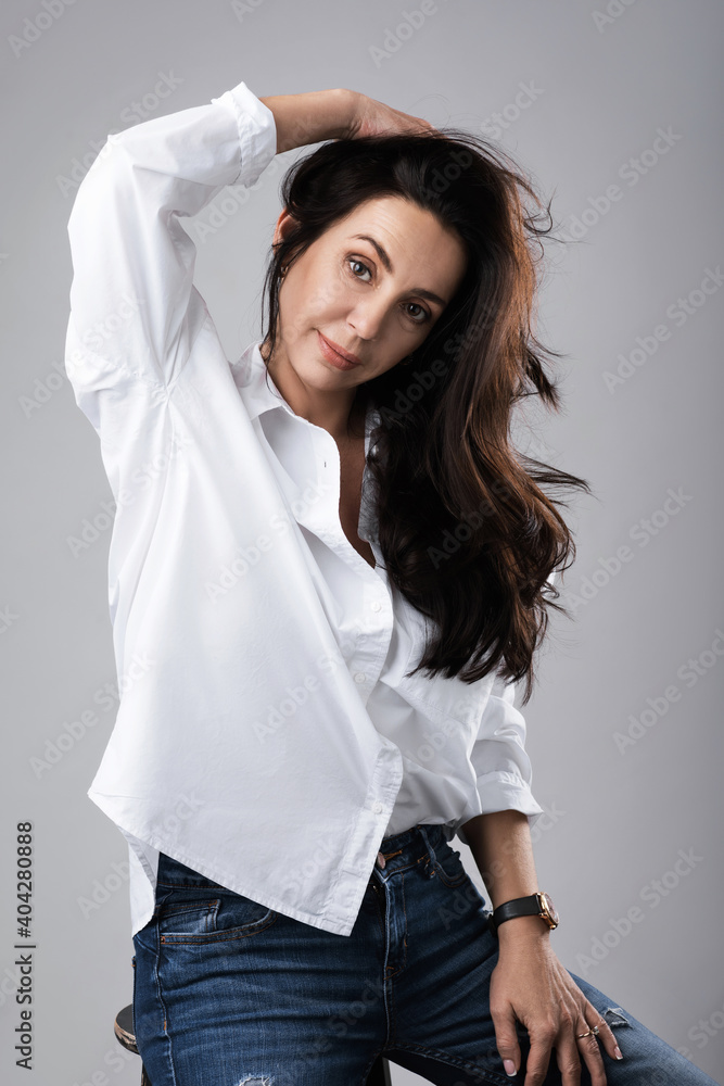 Beautiful middle aged fashion model wearing white shirt and jeans in a ...
