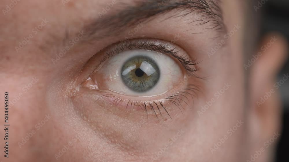 Extreme close up of surprised male opens his eye wide and stares at the ...