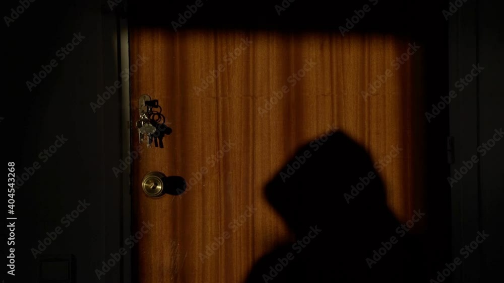 Vidéo Stock Scary shadow of a man in a hood on the door. Silhouette of ...