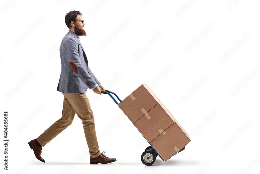 Bearded man walking and pushing a hand-truck with a pile of cardboard ...