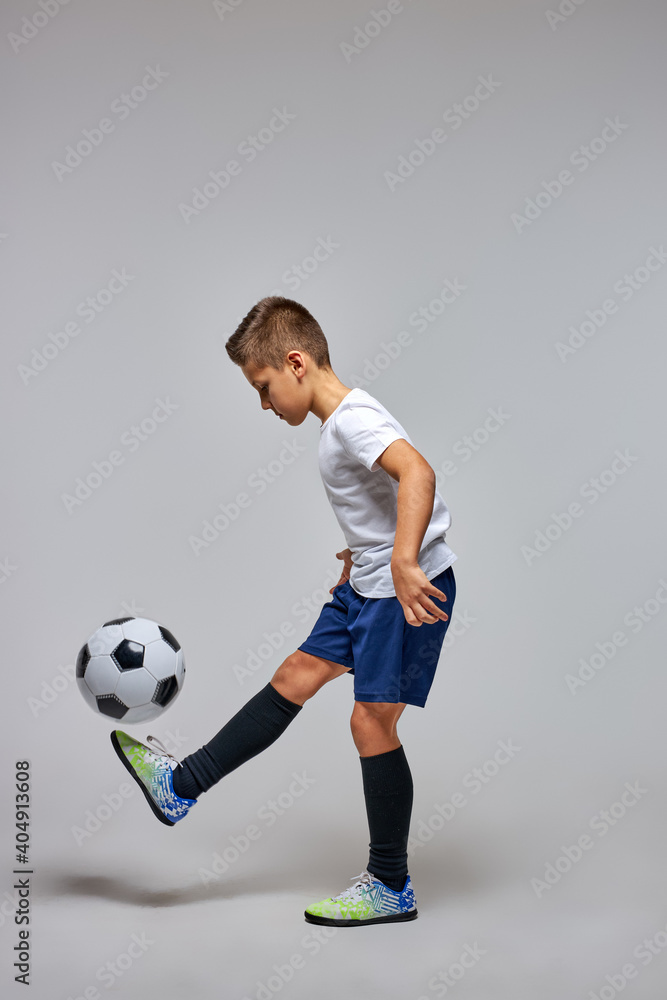 boy professionally training with soccer ball in studio, preparing for ...