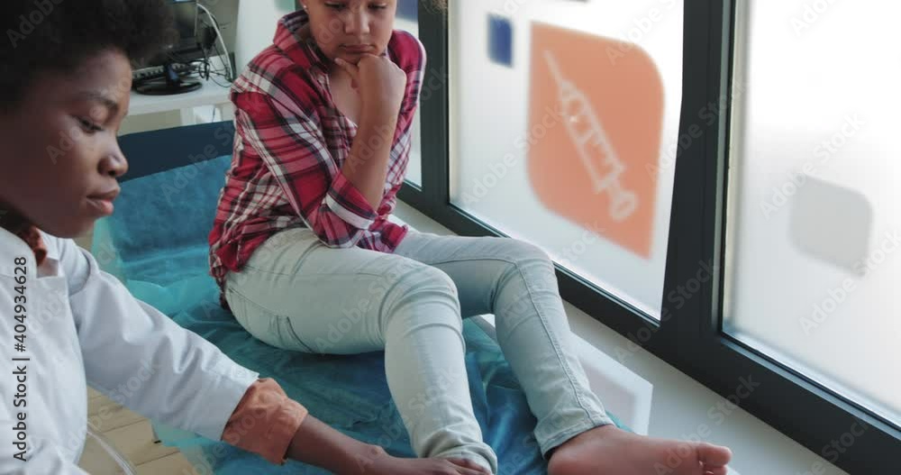 Leg Dislocation First Aid. The doctor examines the leg of a black girl ...