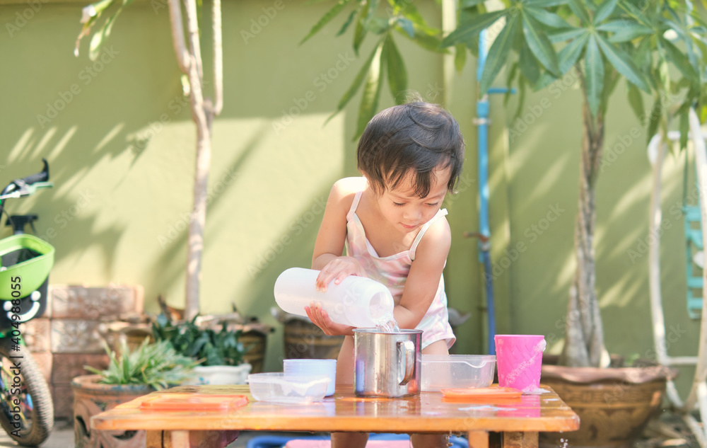 Asian toddler girl having fun pouring water into cup, Wet Pouring ...