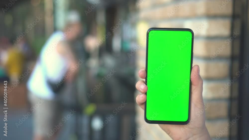 Close up hands woman holding phone with vertical green screen on busy ...
