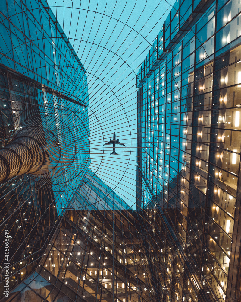 Low-angle photo of commercial plane flying over buildings Stock Photo ...