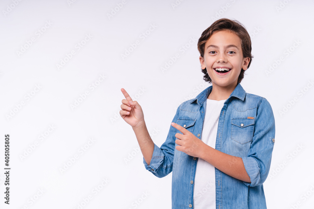 Amazed young male kid pointing at copy space isolated over white ...