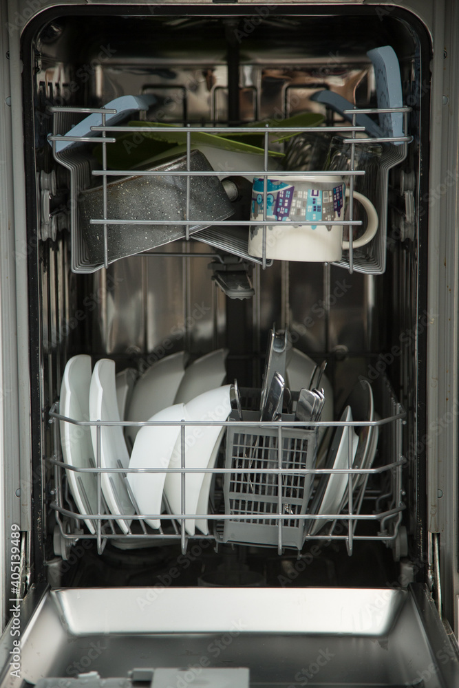 The photo shows an open dishwasher with white dishes. There are pots ...