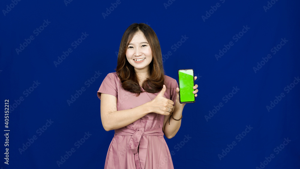 beautiful asian woman pointing green screen in handphone isolated blue ...