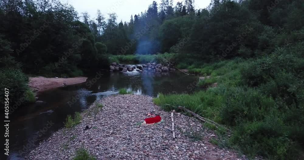 girl in a red cloak is sleeping by fire. The fire is burning, the smoke ...