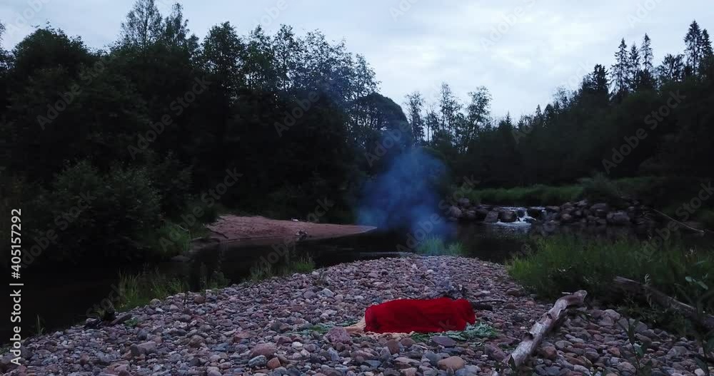 girl in a red cloak is sleeping by the fire. lies on the stones The ...