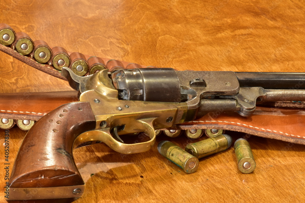 Navy colt firearm with gun belt and bullets on a weathered bar top ...