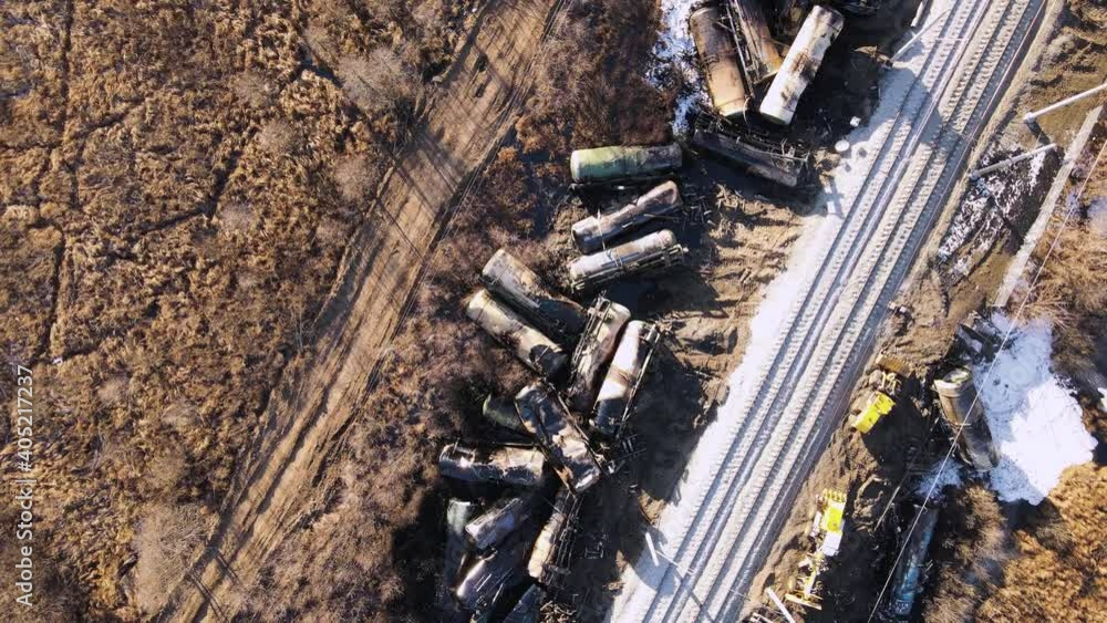 A train wreck on the railroad, scattered cisterns, next to a dirt road ...