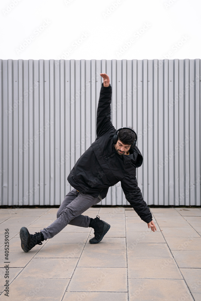 Caucasian white boy dancing with cold clothes black coat listening to music with black ...