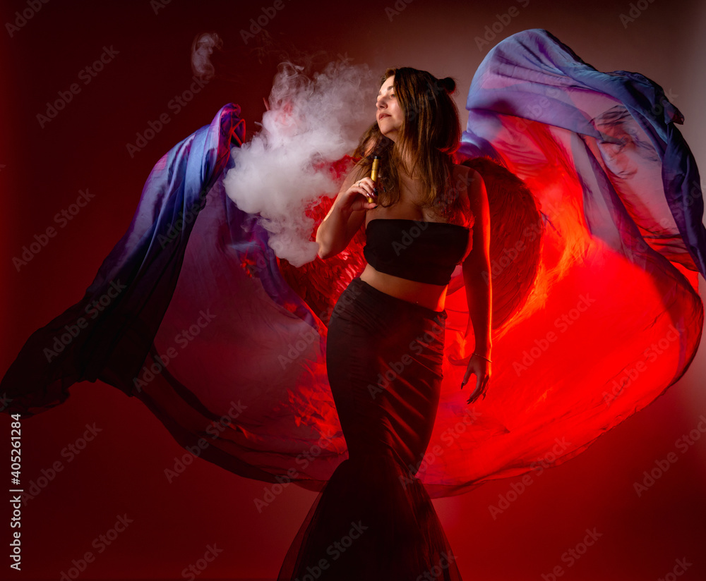Girl with wings smokes a vape. Young girl with an electronic cigarette ...