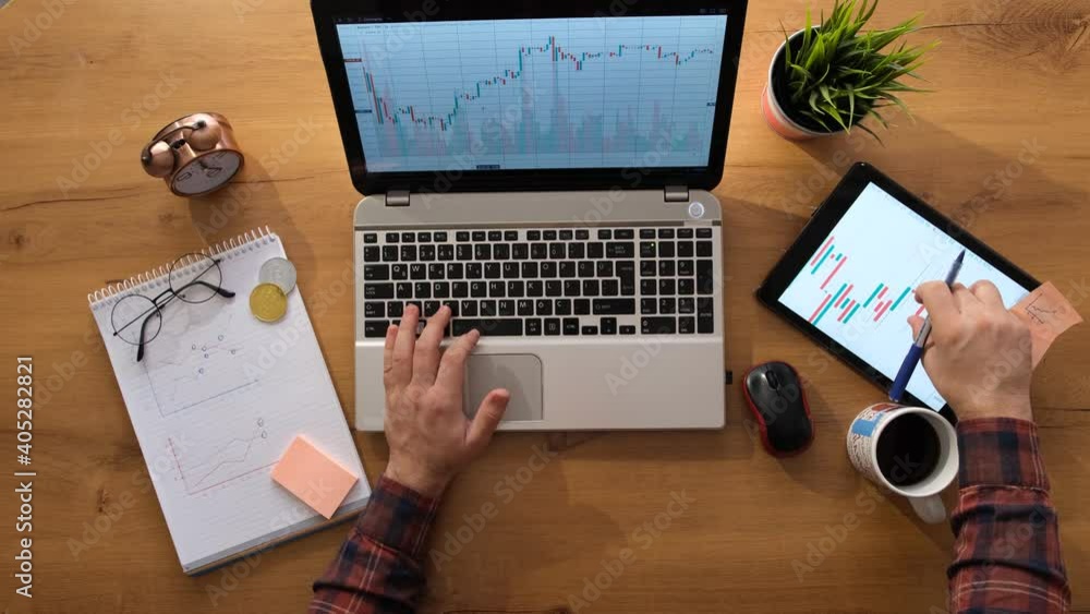 man pointing with pen on paper, looking at leptop screen after checking ...