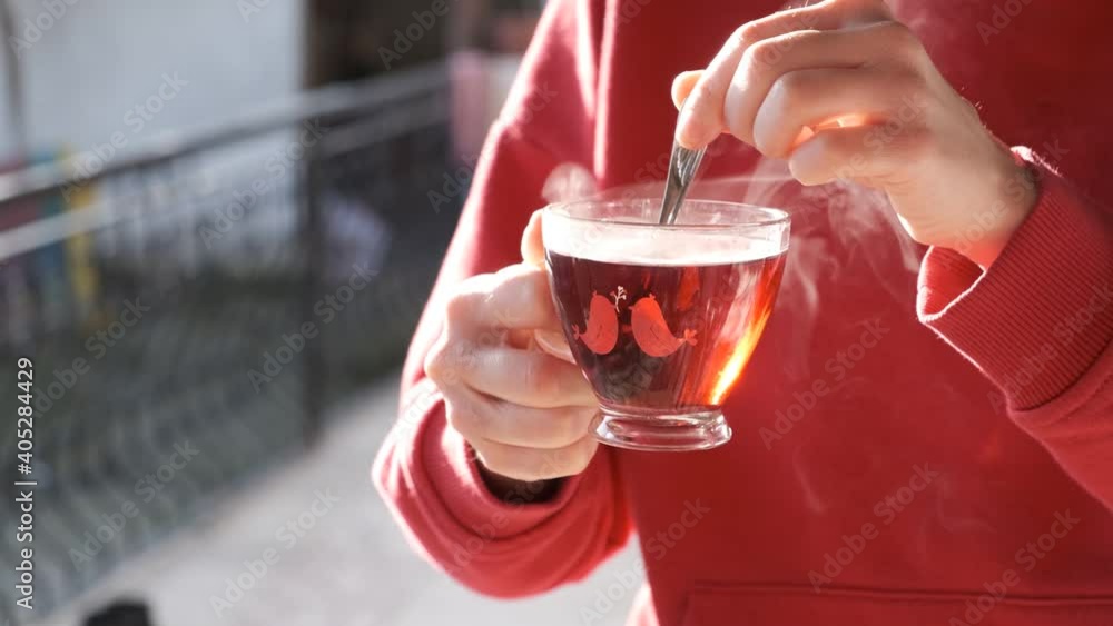Woman mixing hot tea in cold weather. The light hits the tea and the ...
