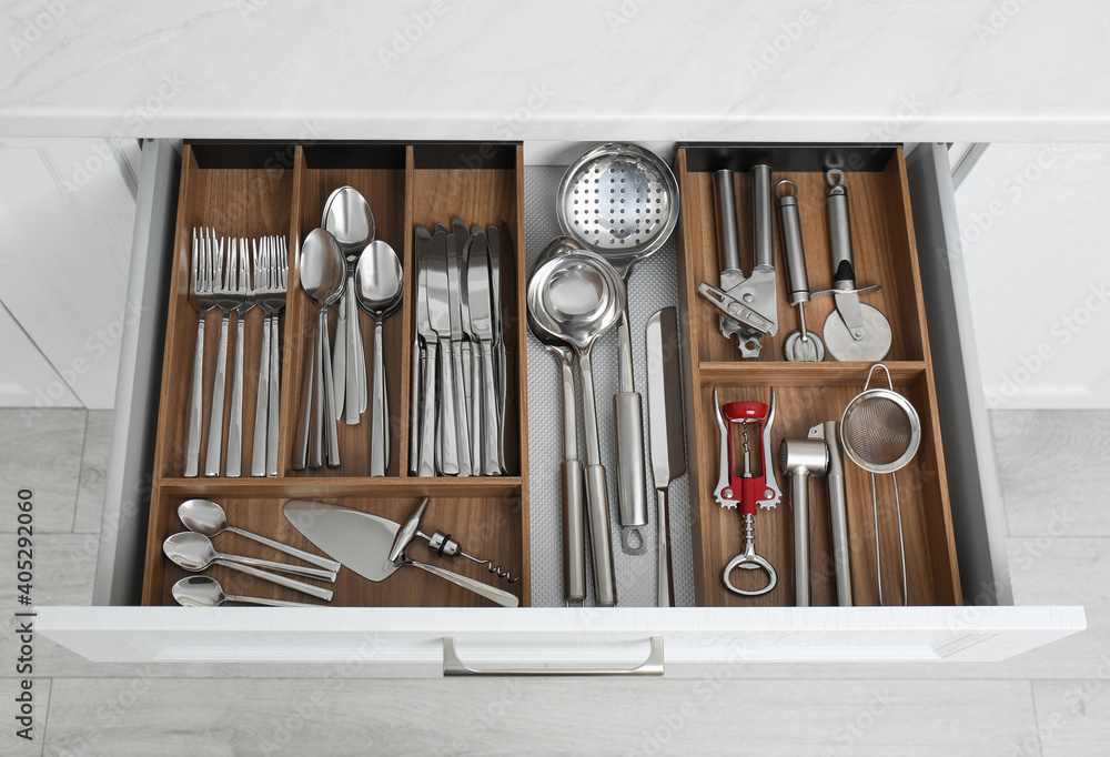 Open drawer with different utensils and cutlery in kitchen, above view ...