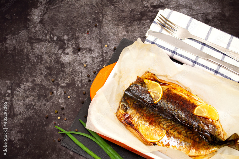 Oven baked mackerel with spices and lemon, next to it a bunch of herbs ...