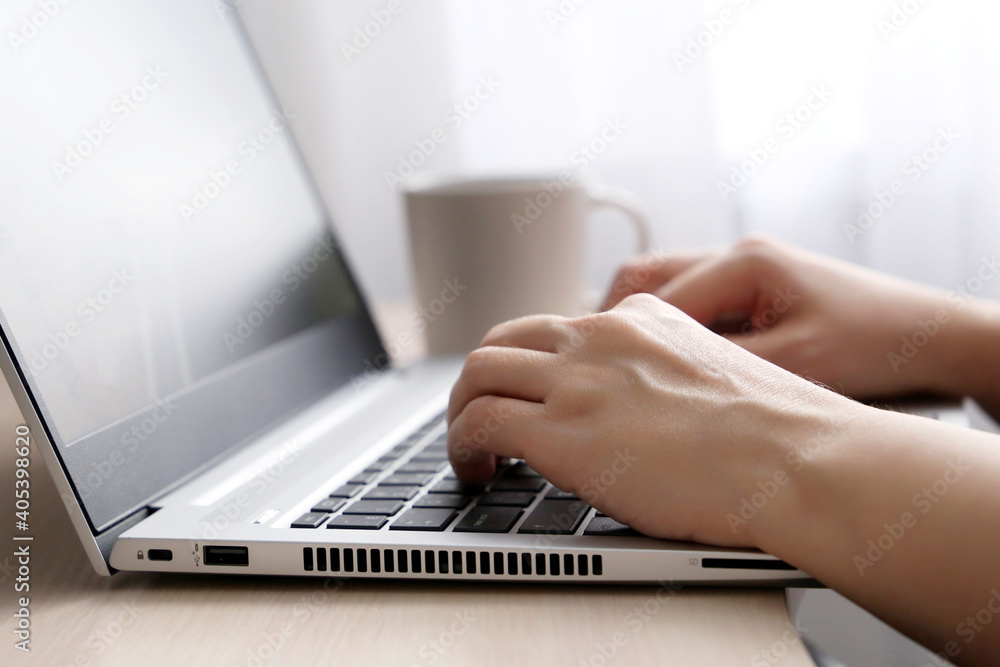Female hands on laptop keyboard on a desk in sunlight. Woman types on ...