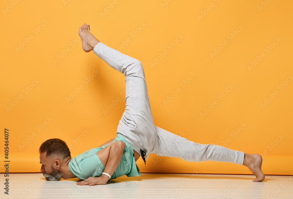 Mature active male practicing chaturanga yoga push-ups with body raised ...