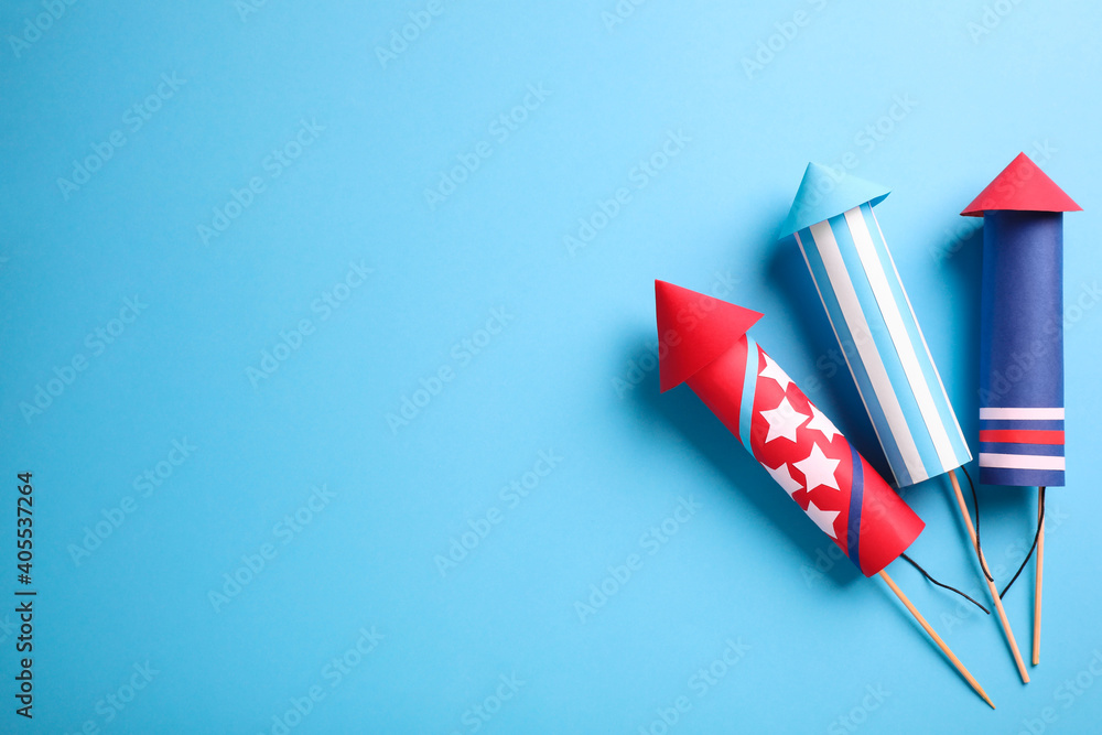 Firework rockets on light blue background, flat lay. Space for text ...