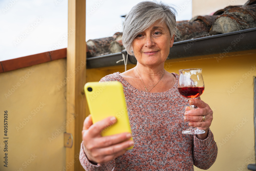 Friendly mature woman 60s drinks red wine calls her friends with phone ...