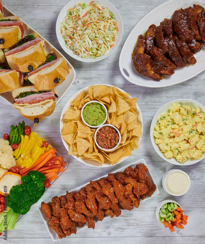 Party food spread with wings, ribs, potato salad, tortilla chips ...