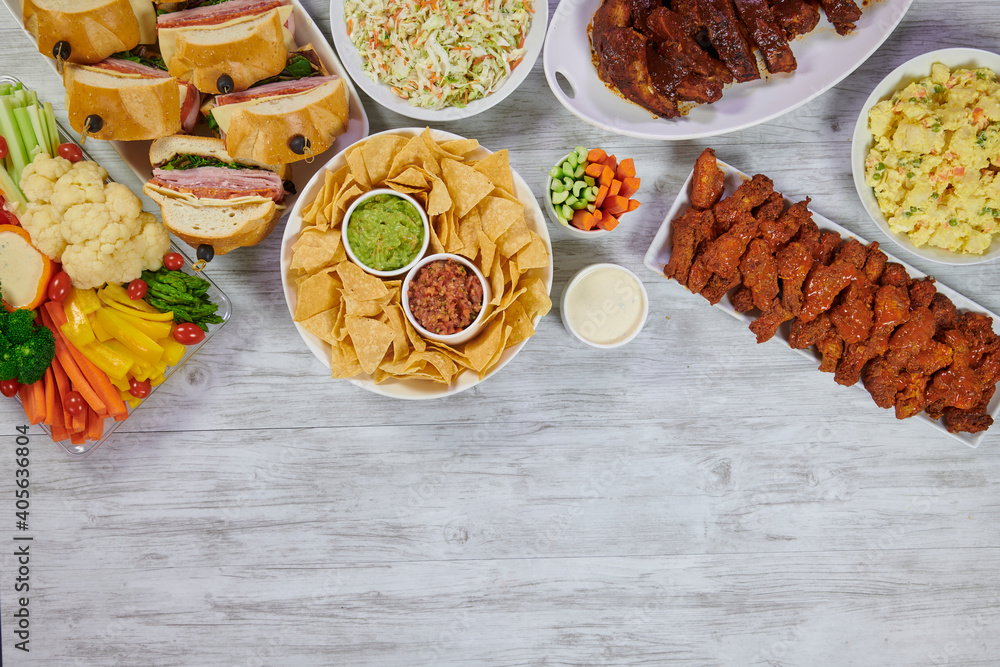Party food spread with wings, ribs, potato salad, tortilla chips ...
