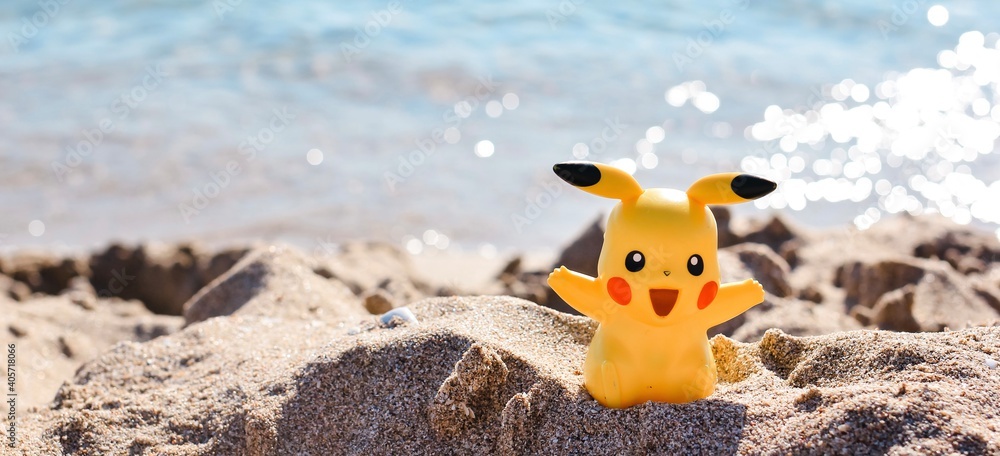 Pikachu figure model sitting on a sandy beach by the sea. Banner. Stock ...