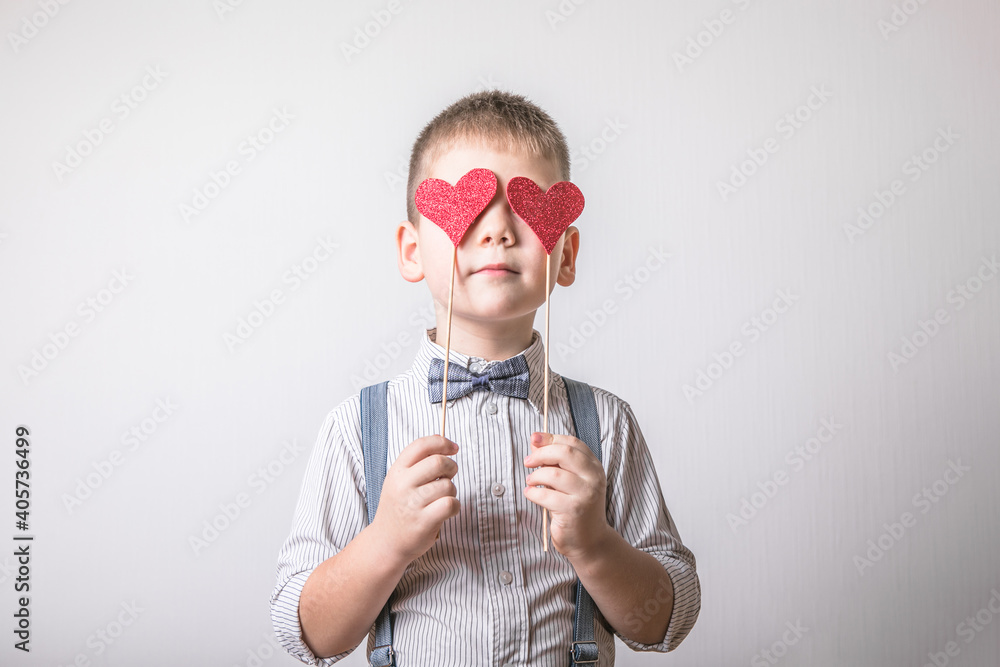 Five year old smiling boy holding a red heart on eyes symbol of love ...