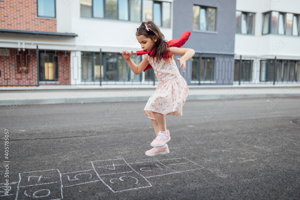 Full view of little girl playing hopscotch with her mother on ...