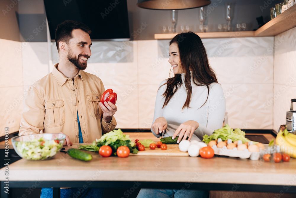 Lovely vegetarian couple is cooking together in the kitchen and using ...
