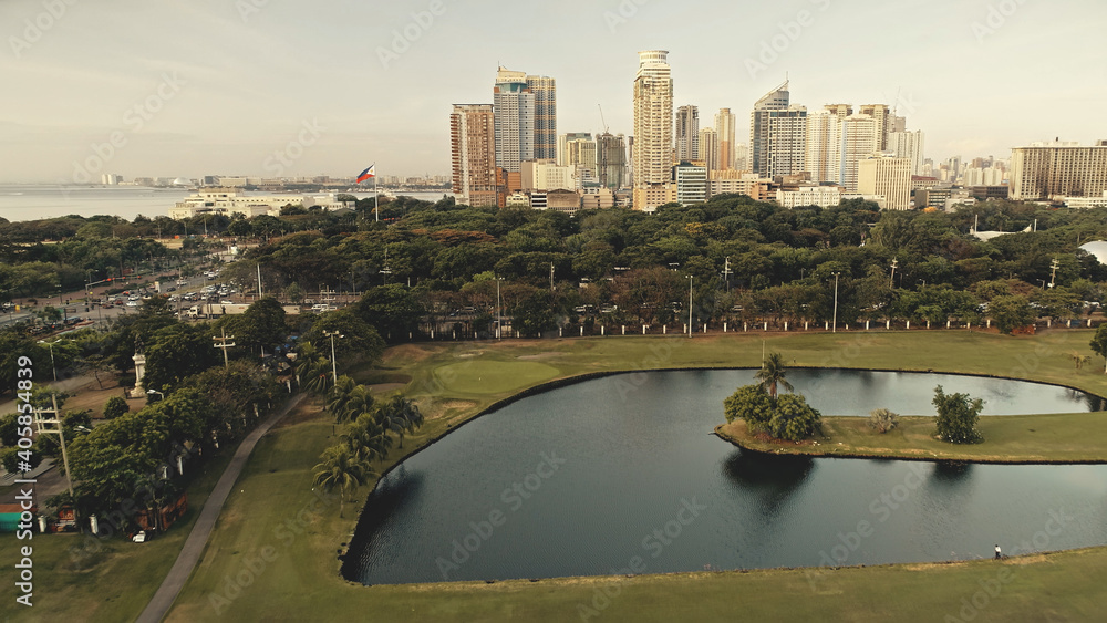 Green park at pond bank at background of sun cityscape aerial. High ...