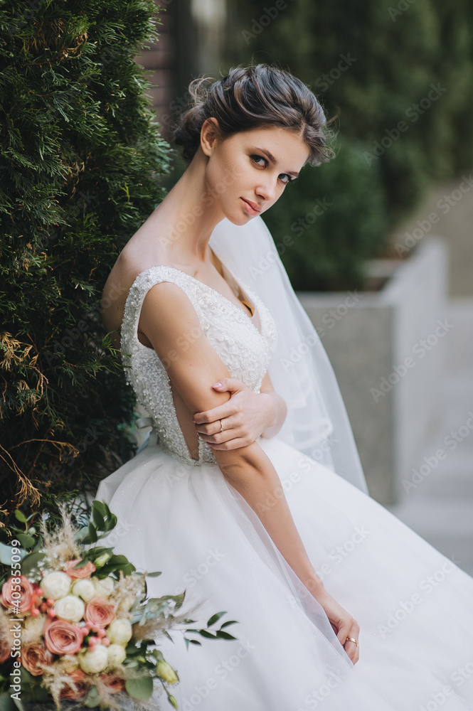 Wedding portrait of a smiling model. A cute curly-haired bride in a ...