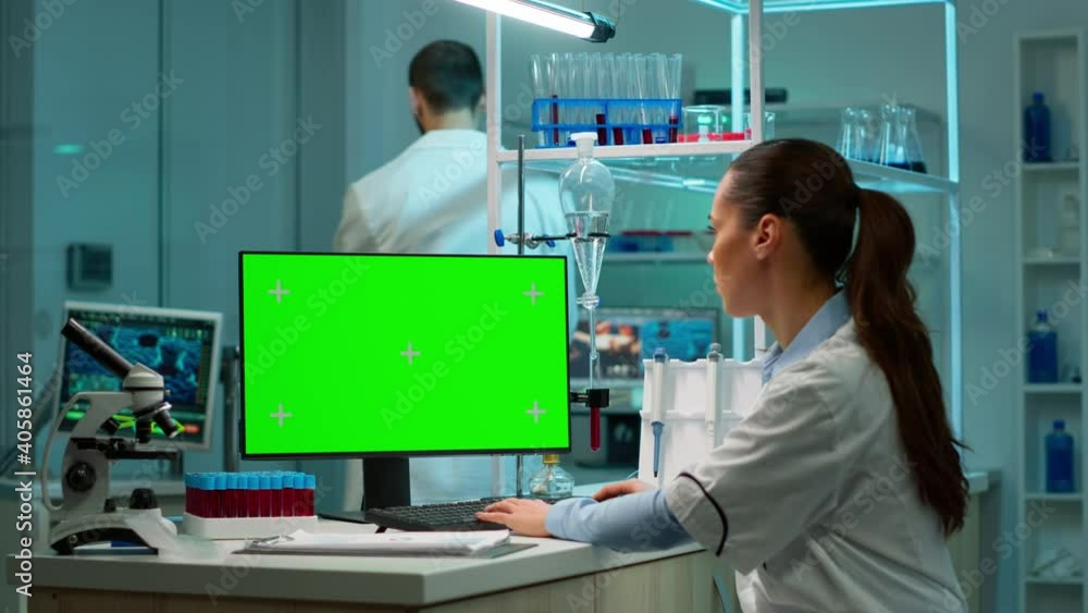 Female scientist working on computer with mock-up green screen in ...