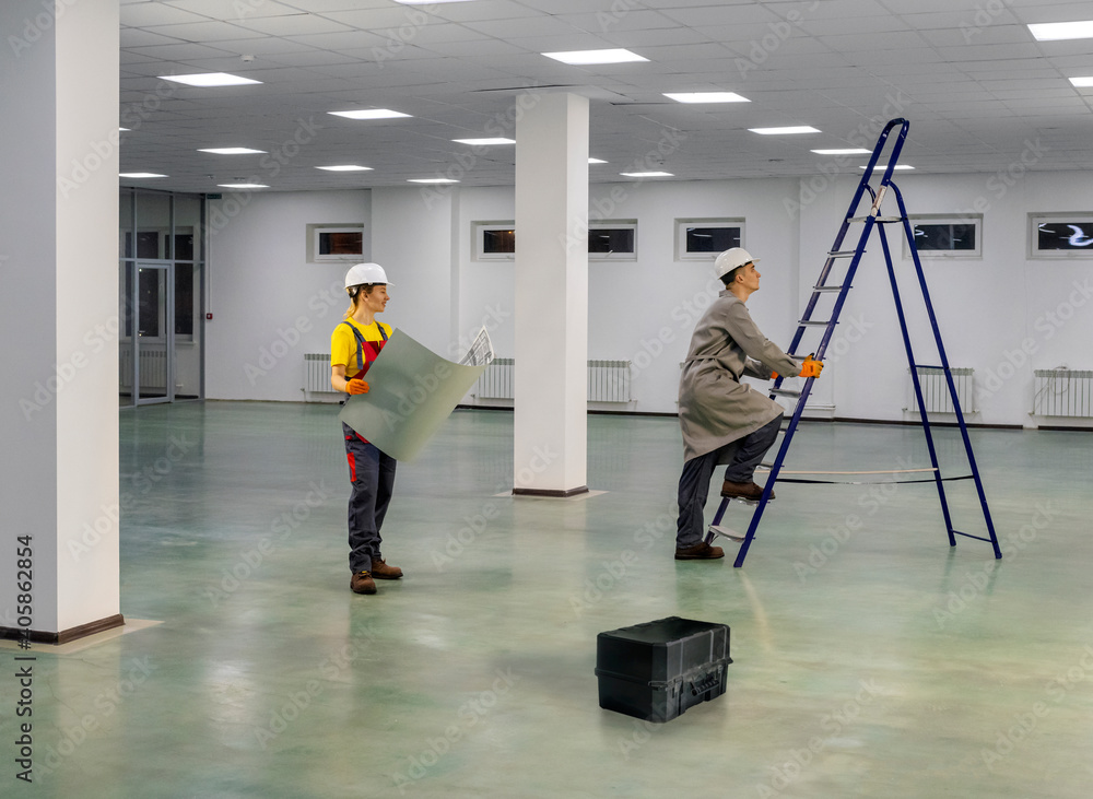 Workers on a ladder check the electrical wires on the ceiling. Workers ...