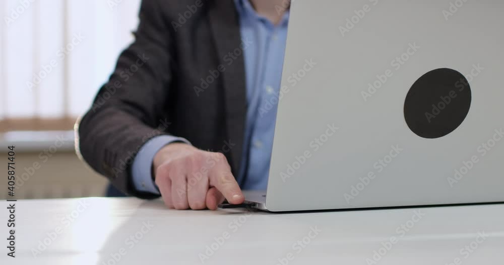 A man in a suit holds an access flash drive key in his hand, inserts ...