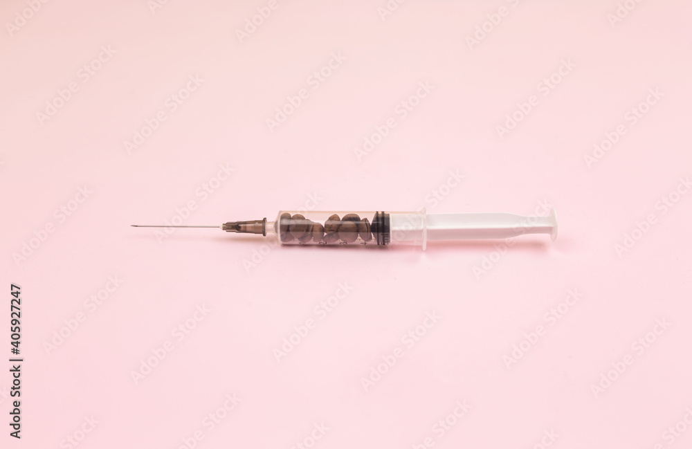 Transparent syringe with coffee beans inside on a pink background. View ...