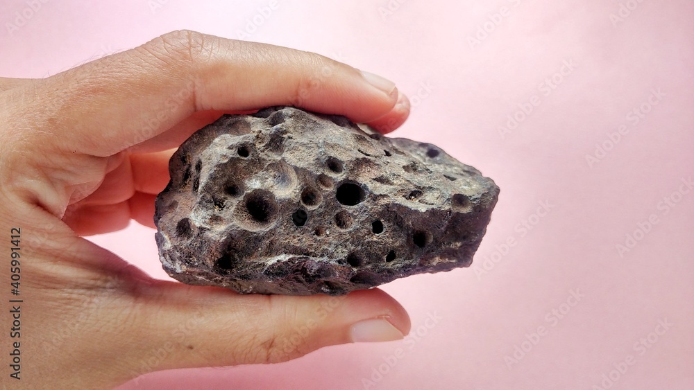 Extrusive volcanic igneous rock, vesicular basalt. Dark brown and ...