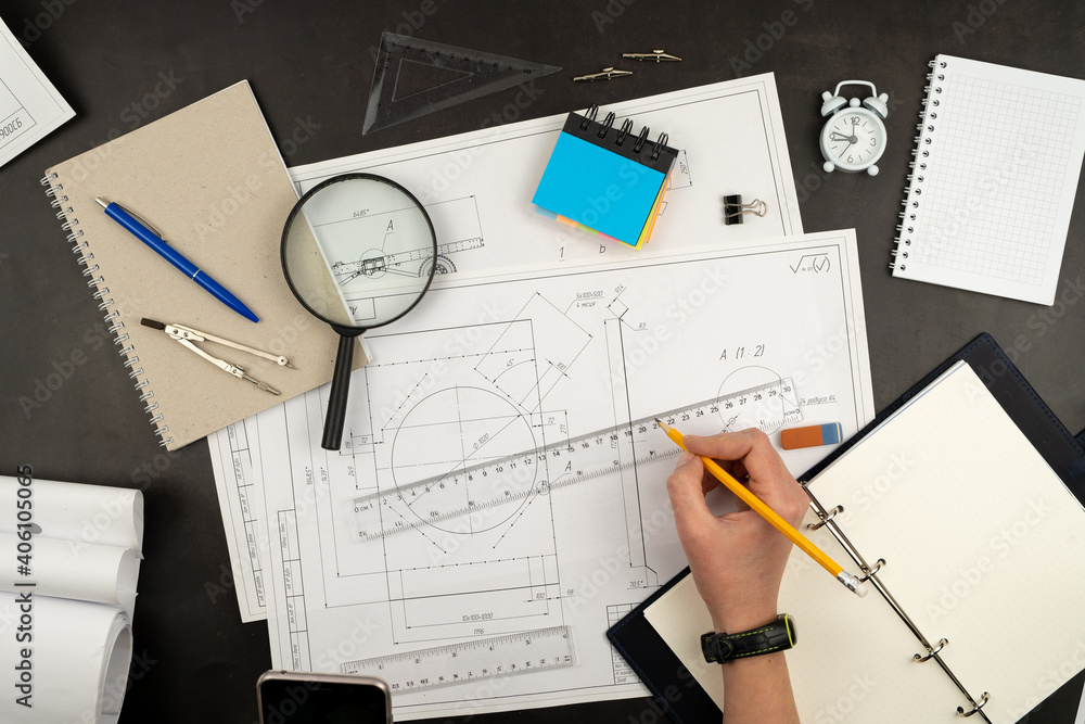 Mechanical drawing on sheets of paper. Hands on the table top view ...