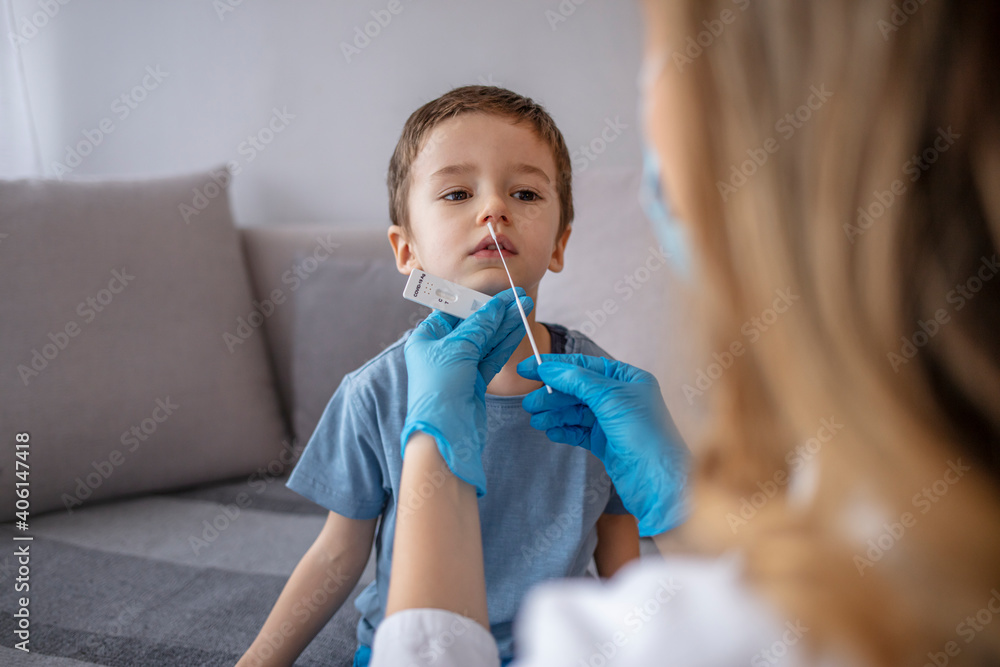 Boy sitting on sofa while going through PCR testing at home due to ...