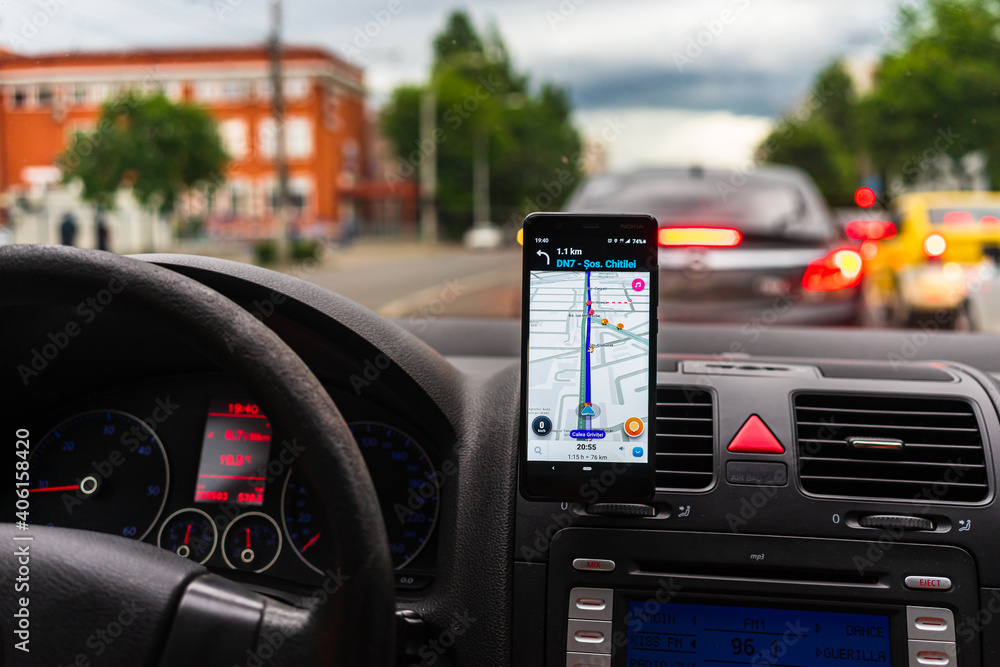 Driving and using waze maps application on smartphone on car dashboard ...