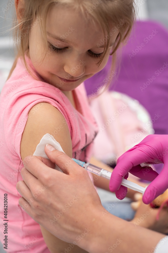 The doctor is giving a little girl an injection. The child stares in a ...